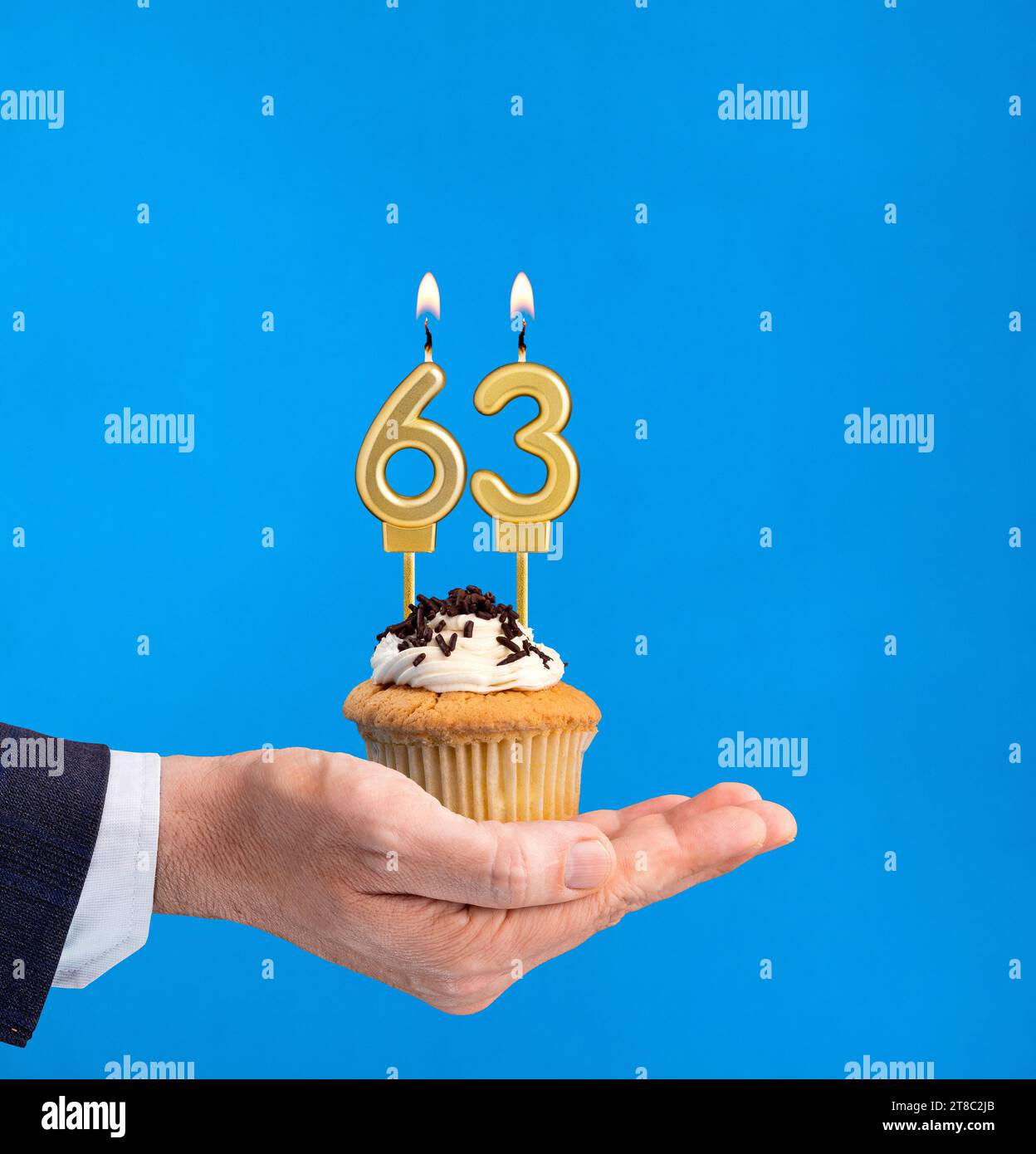 Hand holding a cupcake with the number 63 candle - Birthday on blue ...