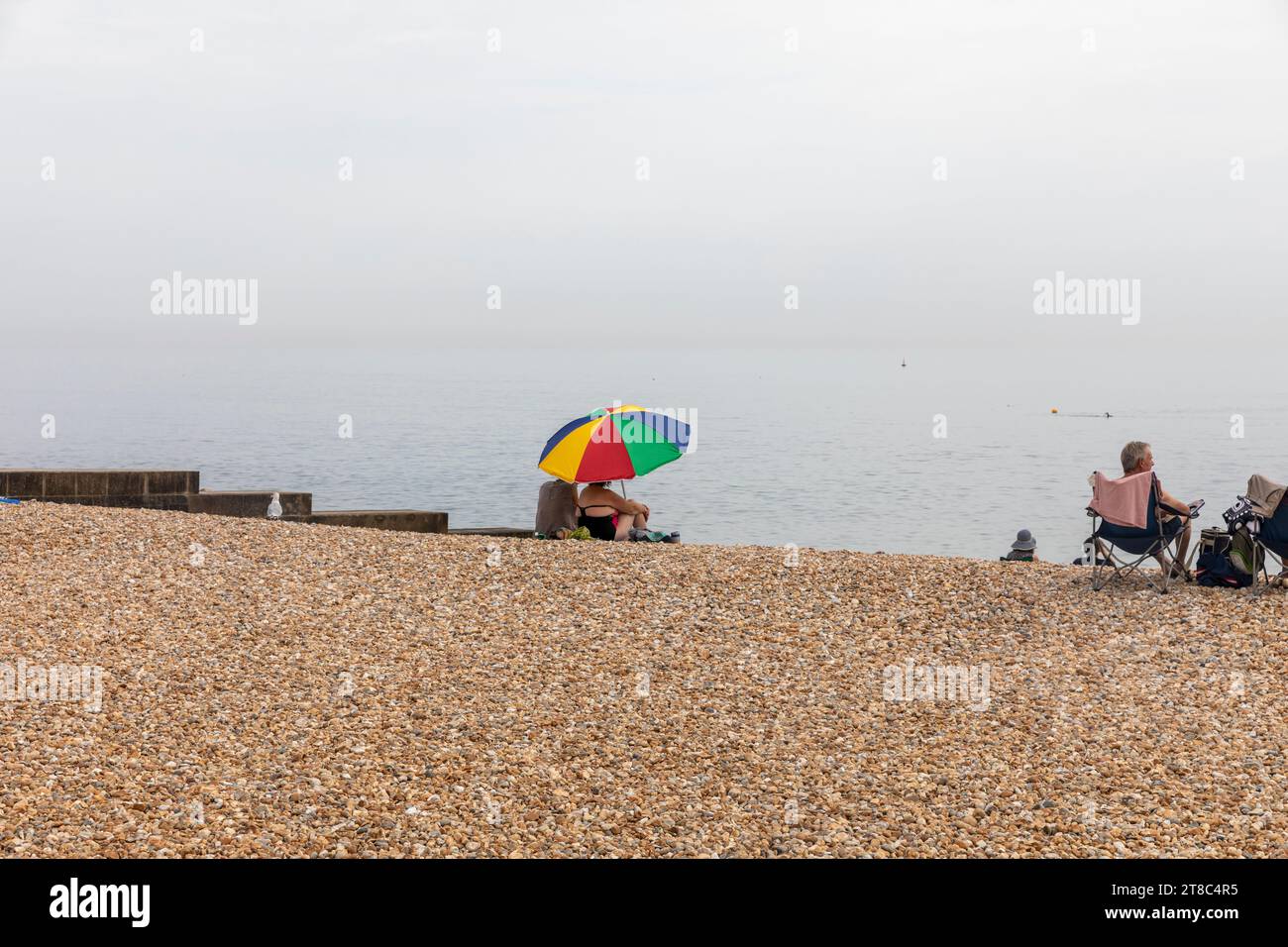 Lyme Regis beachgoers on pebble stone beach autumn 2023, beachgoers ...