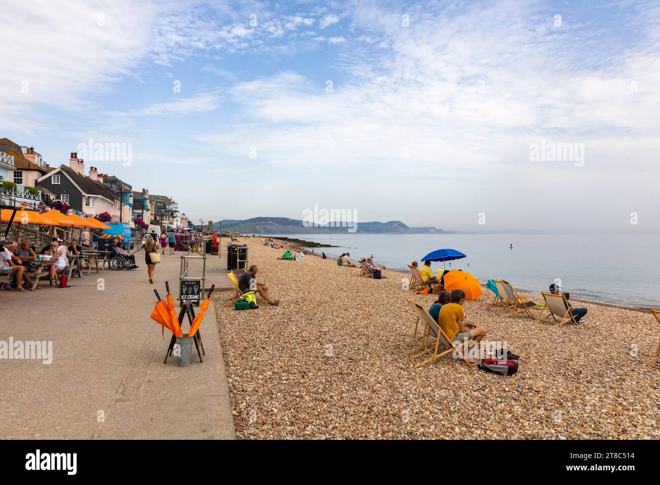 Lyme Regis beachgoers on pebble stone beach autumn 2023, beachgoers ...