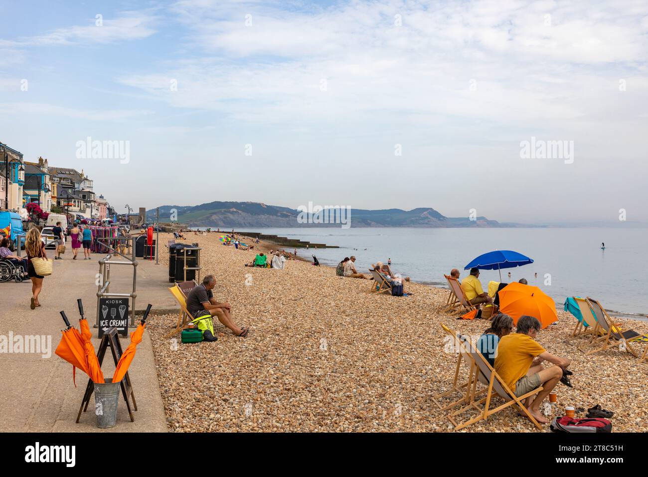 Lyme Regis beachgoers on pebble stone beach autumn 2023, beachgoers ...