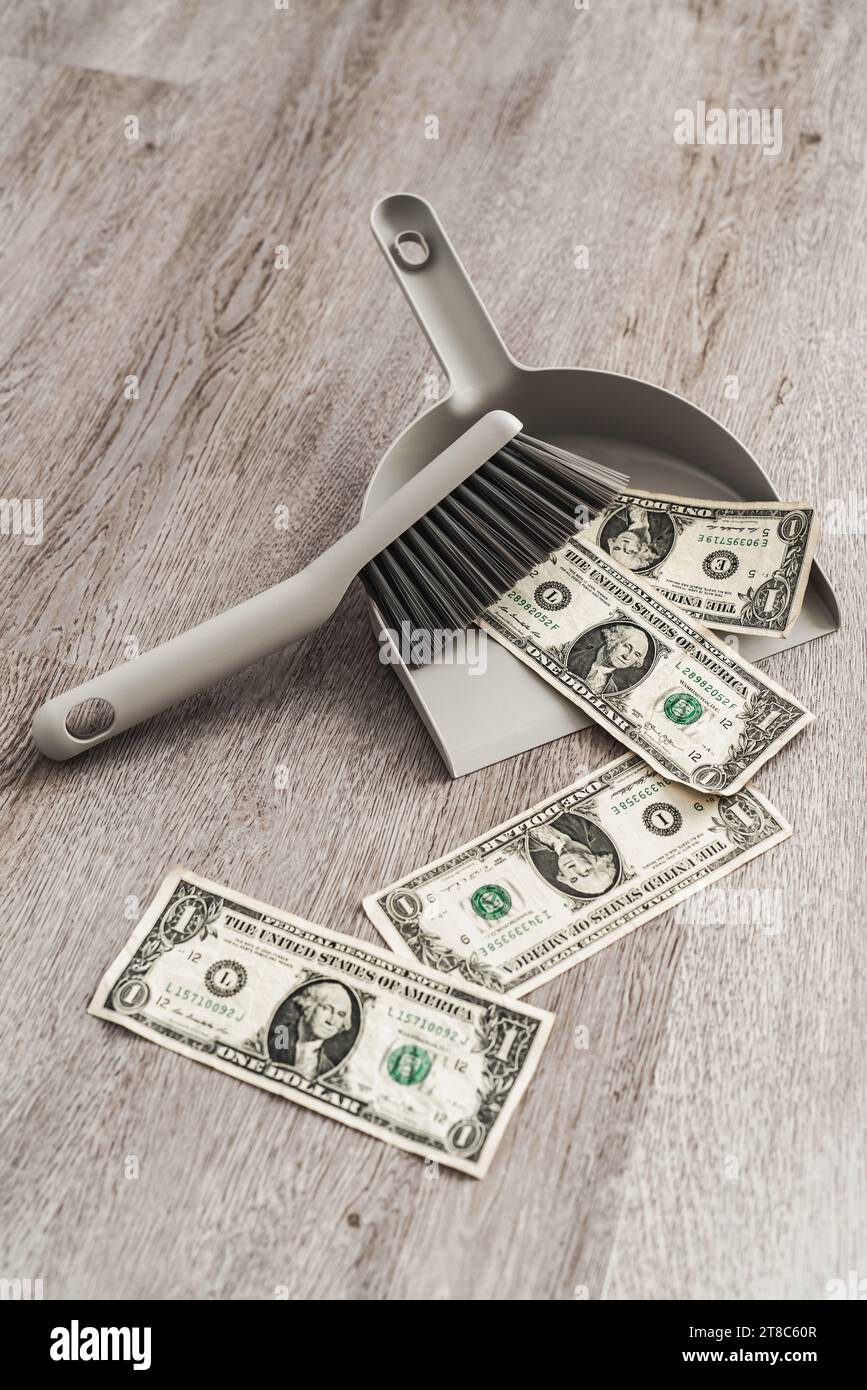 Dustpan and brush alongside scattered one-dollar bills on the floor ...