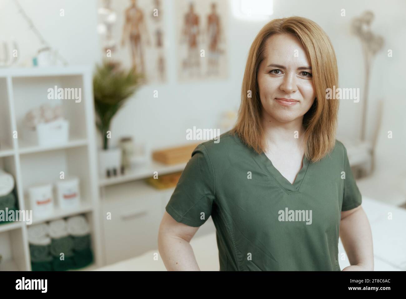 Healthcare time. happy female medical massage therapist in massage cabinet looking at camera ...