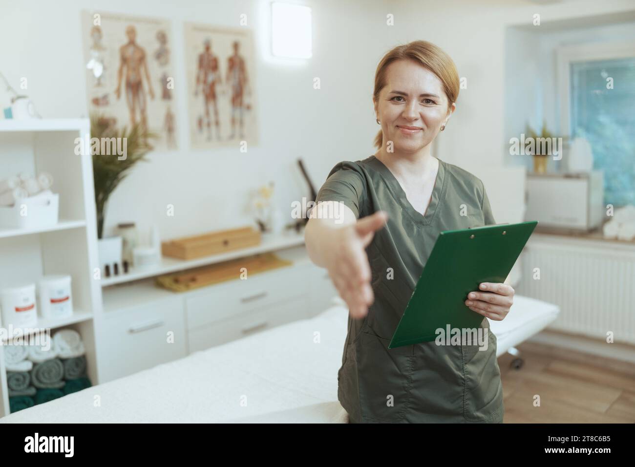 Healthcare time. happy massage therapist woman in massage cabinet with clipboard Stock Photo - Alamy