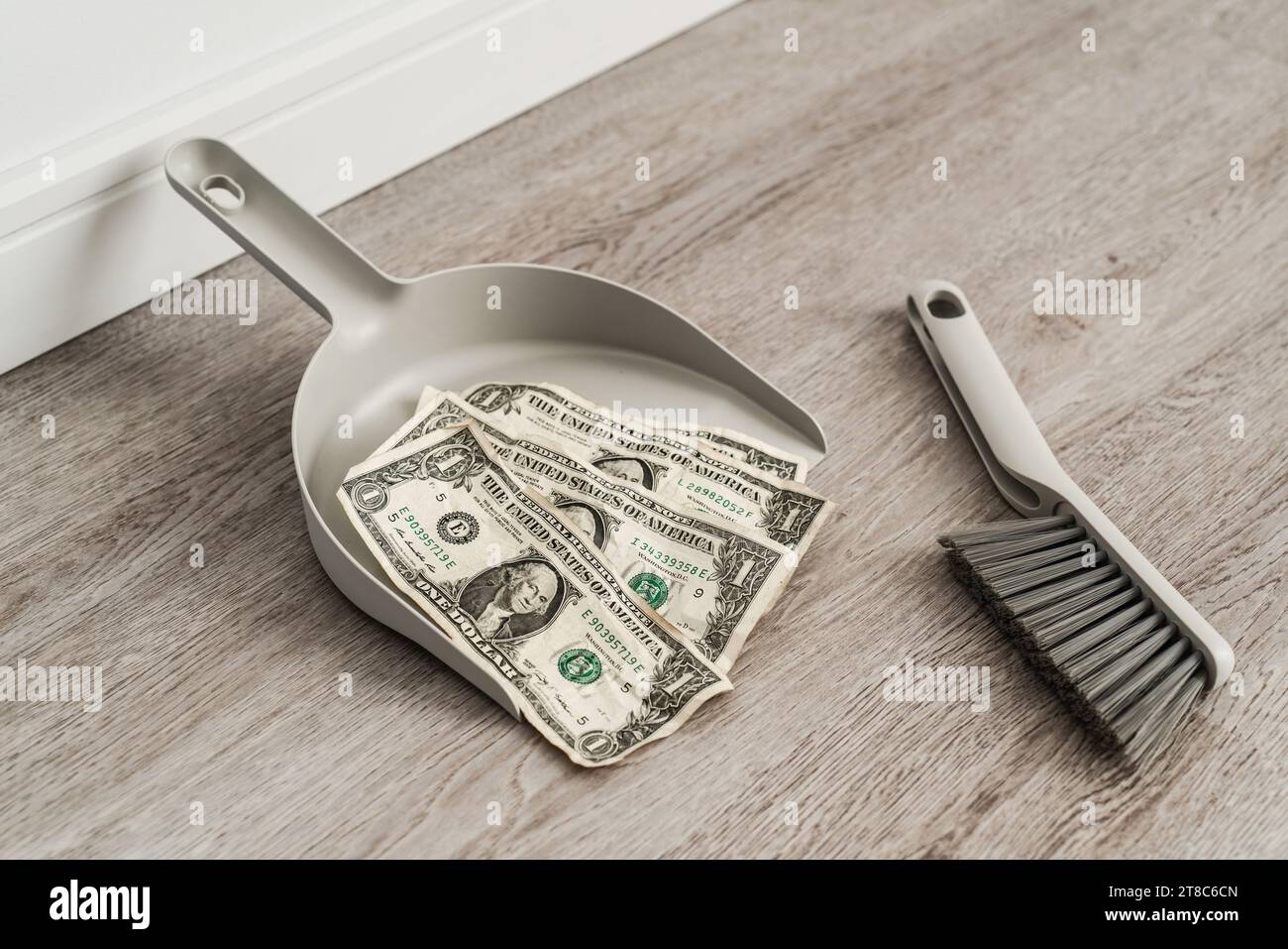 Dustpan and brush alongside scattered one-dollar bills on the floor ...