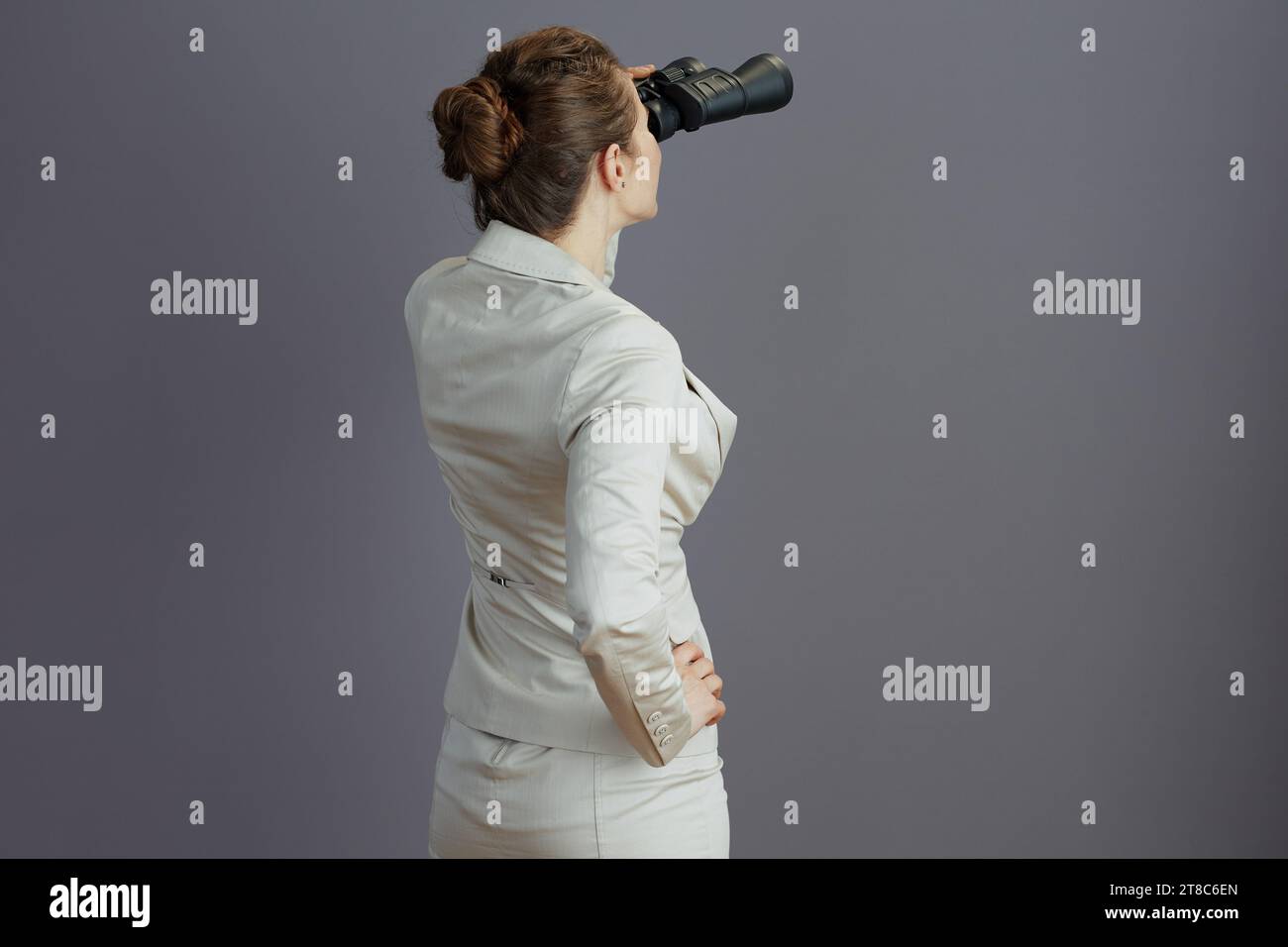 Seen from behind female employee in a light business suit with ...