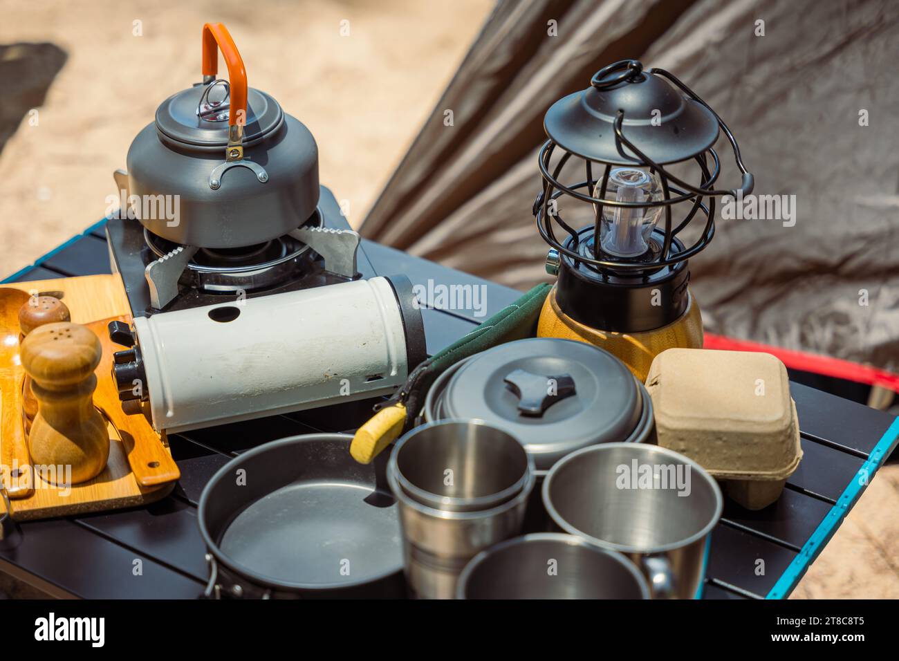 Camping essentials neatly arranged at a beachfront tent, kettle, pot ...