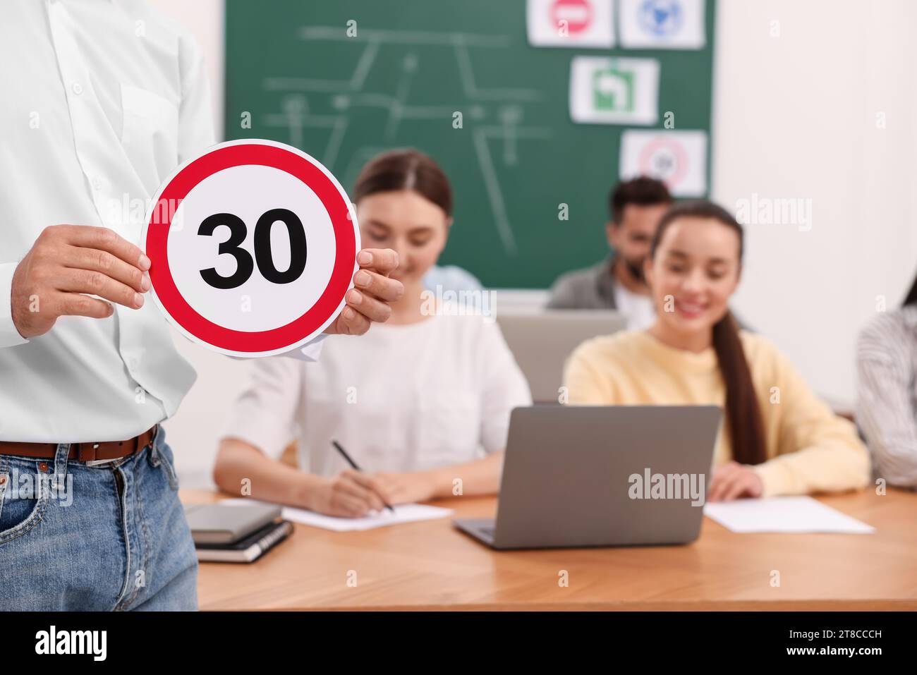 Teacher showing Speed Limit road sign during lesson in driving school ...