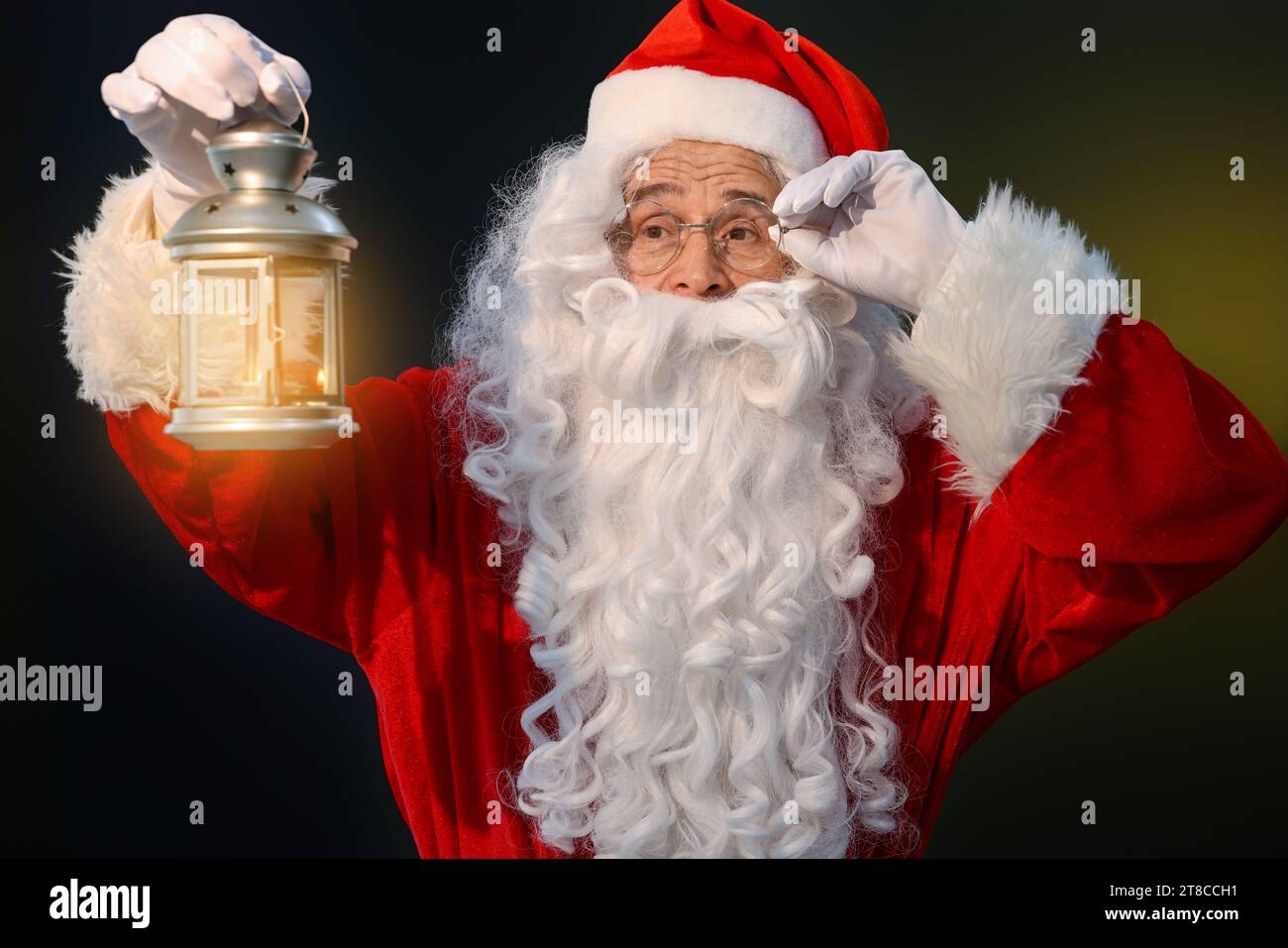 Santa Claus holding Christmas lantern with burning candle on dark ...