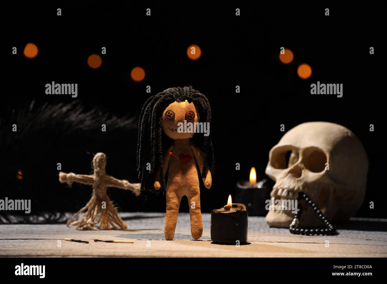 Female voodoo doll with pin in heart and ceremonial items on wooden ...