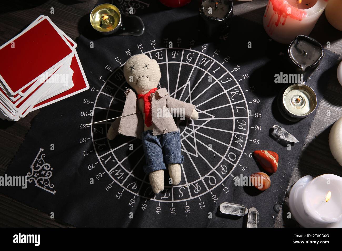 Voodoo doll pierced with needle surrounded by ceremonial items on table ...