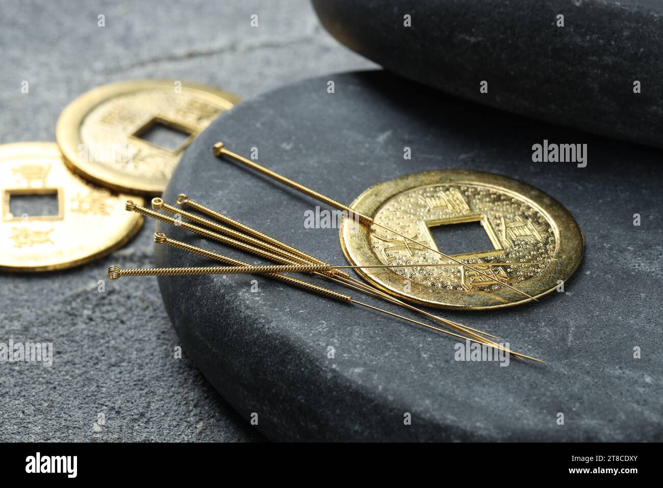 Acupuncture needles, ancient coins and stone on grey textured table ...