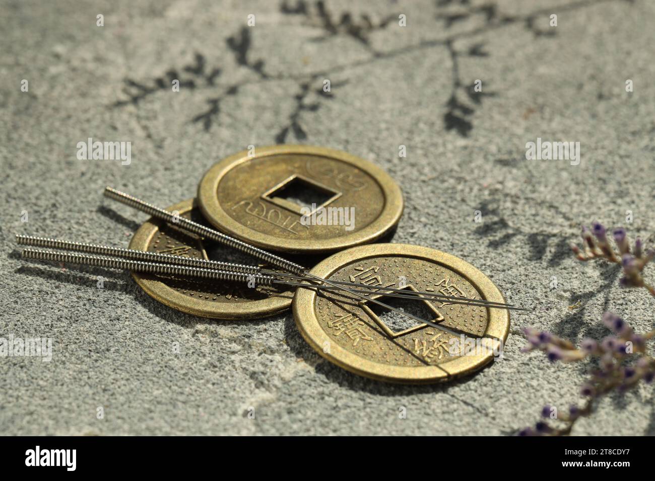 Acupuncture needles and ancient coins on stone surface Stock Photo - Alamy
