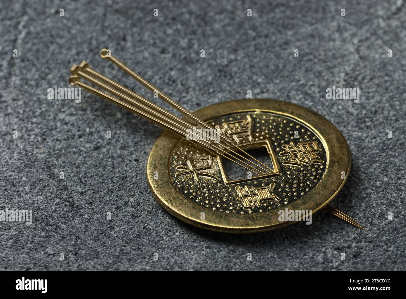 Acupuncture needles and ancient coin on grey textured table, closeup ...