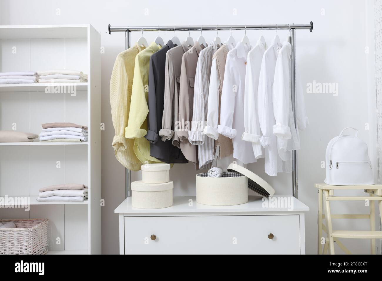 Wardrobe organization. Rack with different stylish clothes, chest of ...
