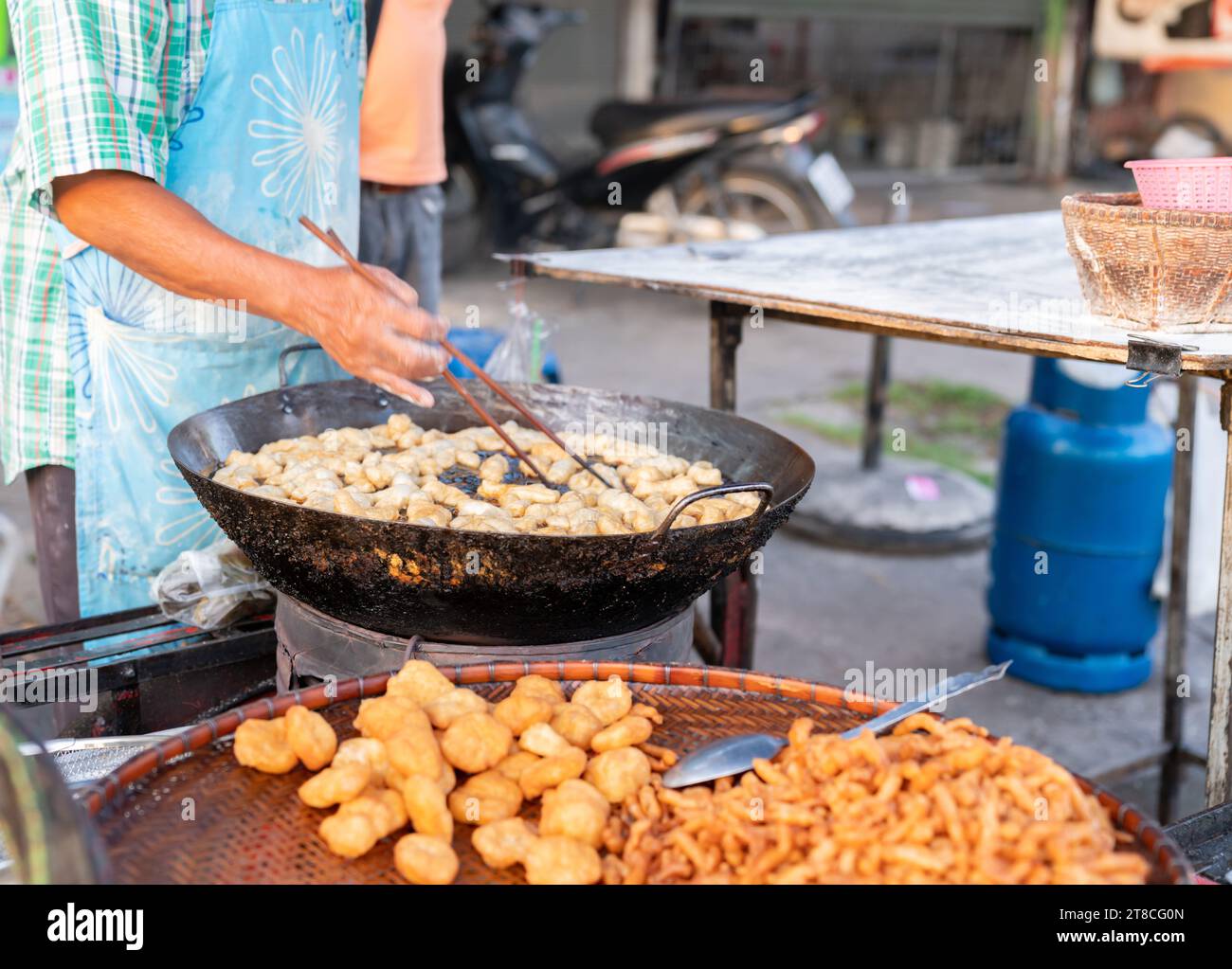 The man frying deep fried dough sticks in pan of hot cooking oil. The ...