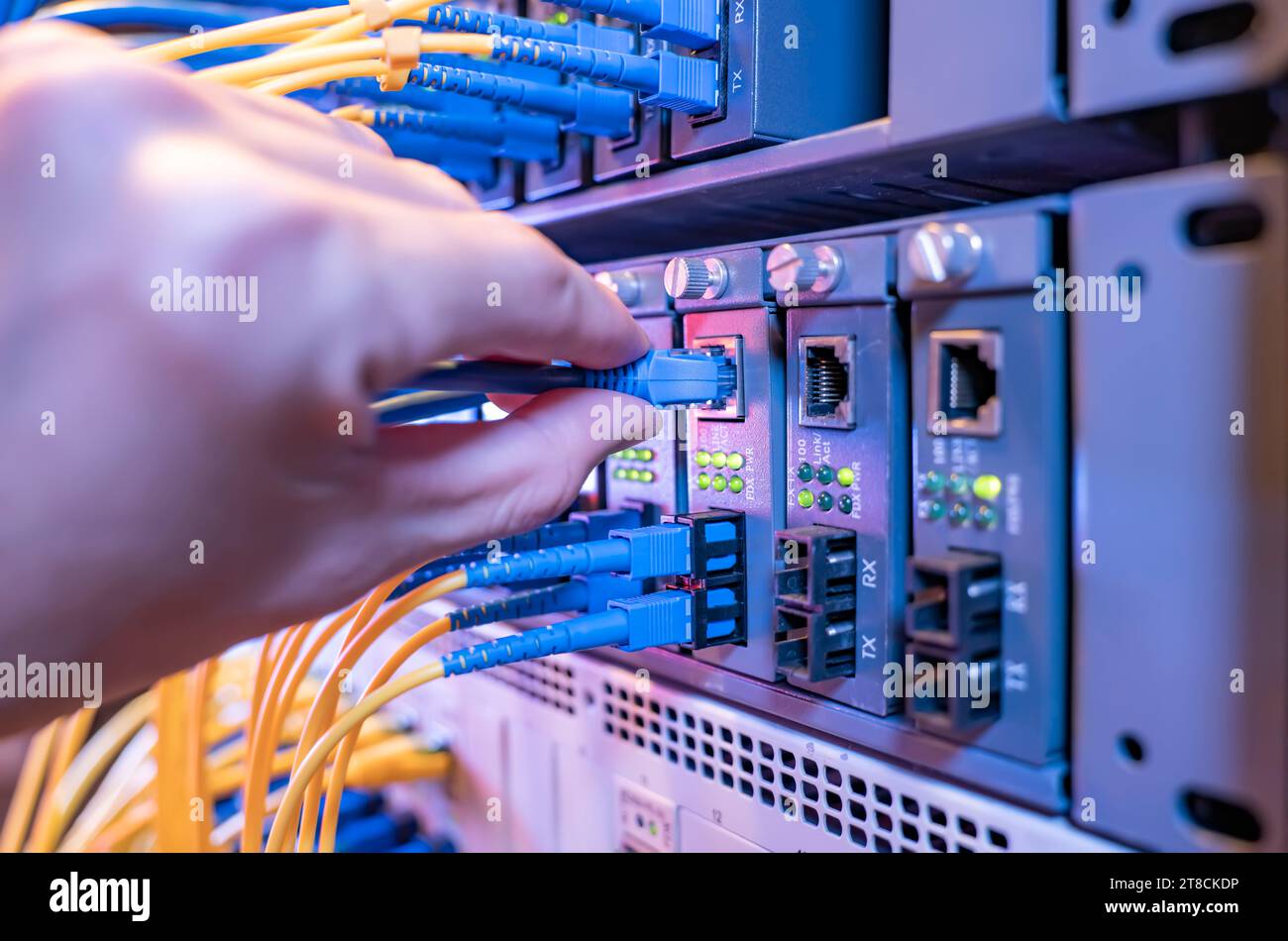 man working in network server room with Fiber Optic cables connected to ...