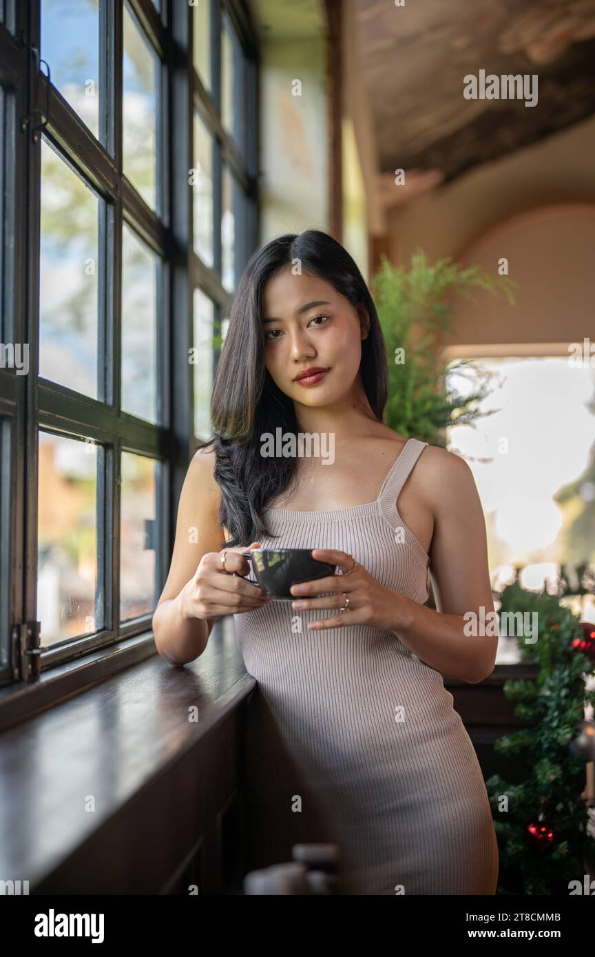 Young beautiful classy Asian woman having a coffee break while leaning ...
