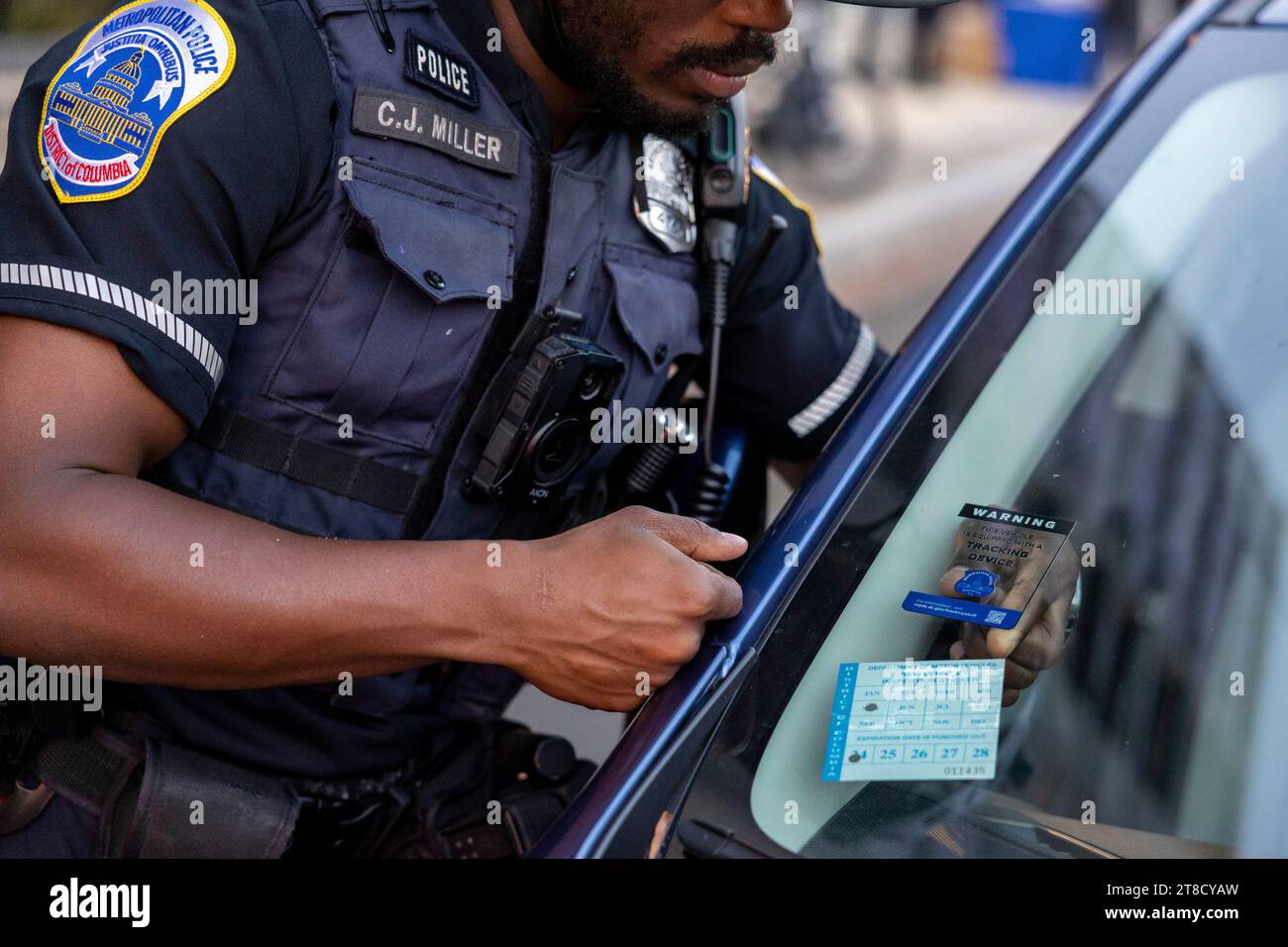 Metropolitan Police Department officer Cyrus Miller puts a sticker on a ...