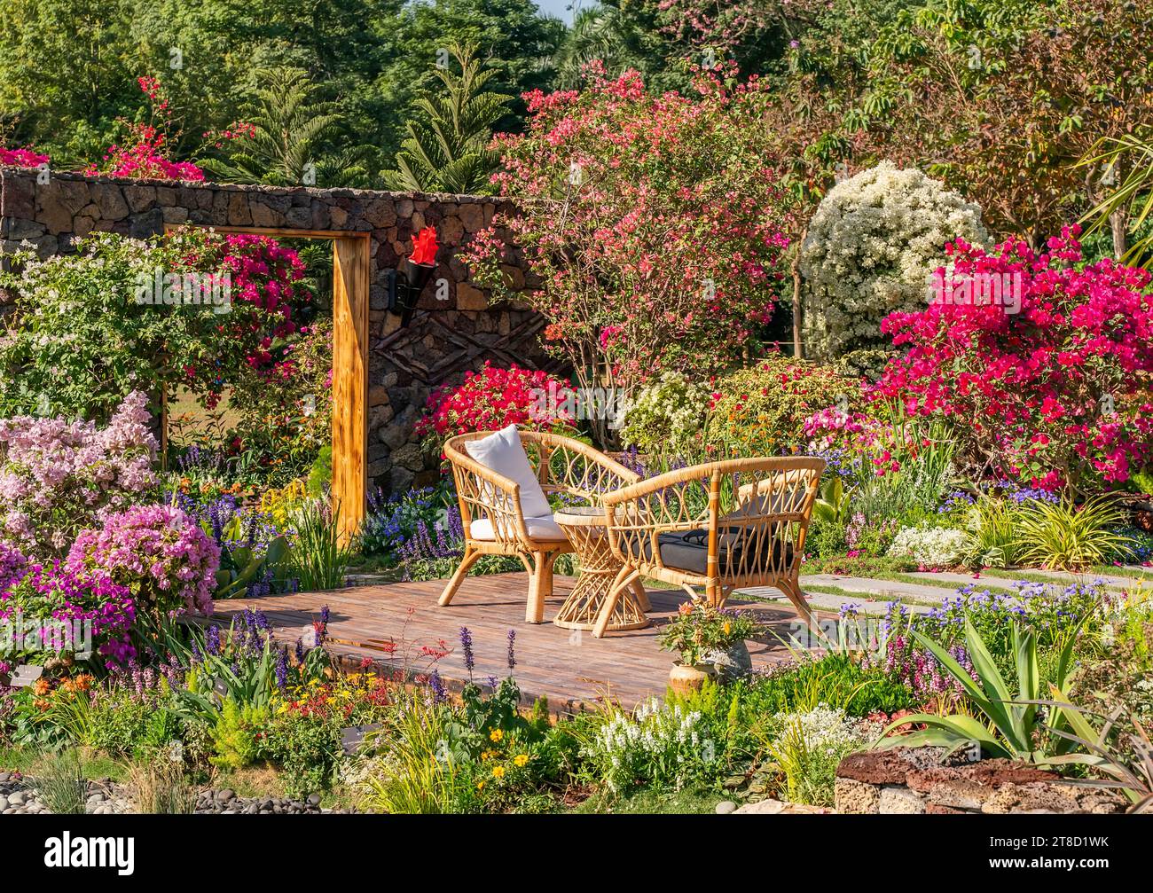 Garden decorated with outdoor wicker furniture and growing flowers in ...