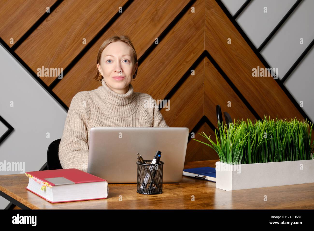 A woman sits at a table, using her laptop with wireless technology ...