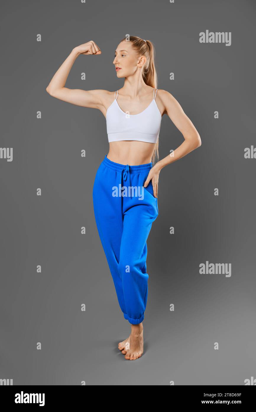 Barefoot sportive woman shows biceps muscle Stock Photo - Alamy