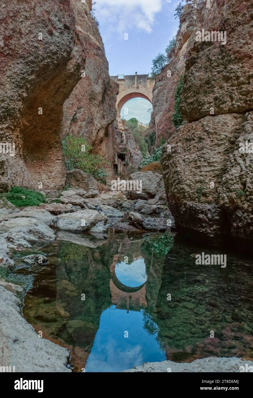 stone bridge over a cliff reflected in the waters of the river with a ...