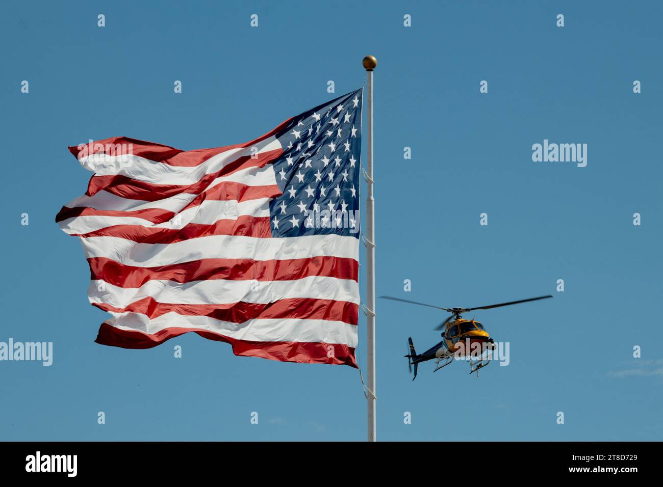 A a helicopter flying next to the American flag floating in the wind ...