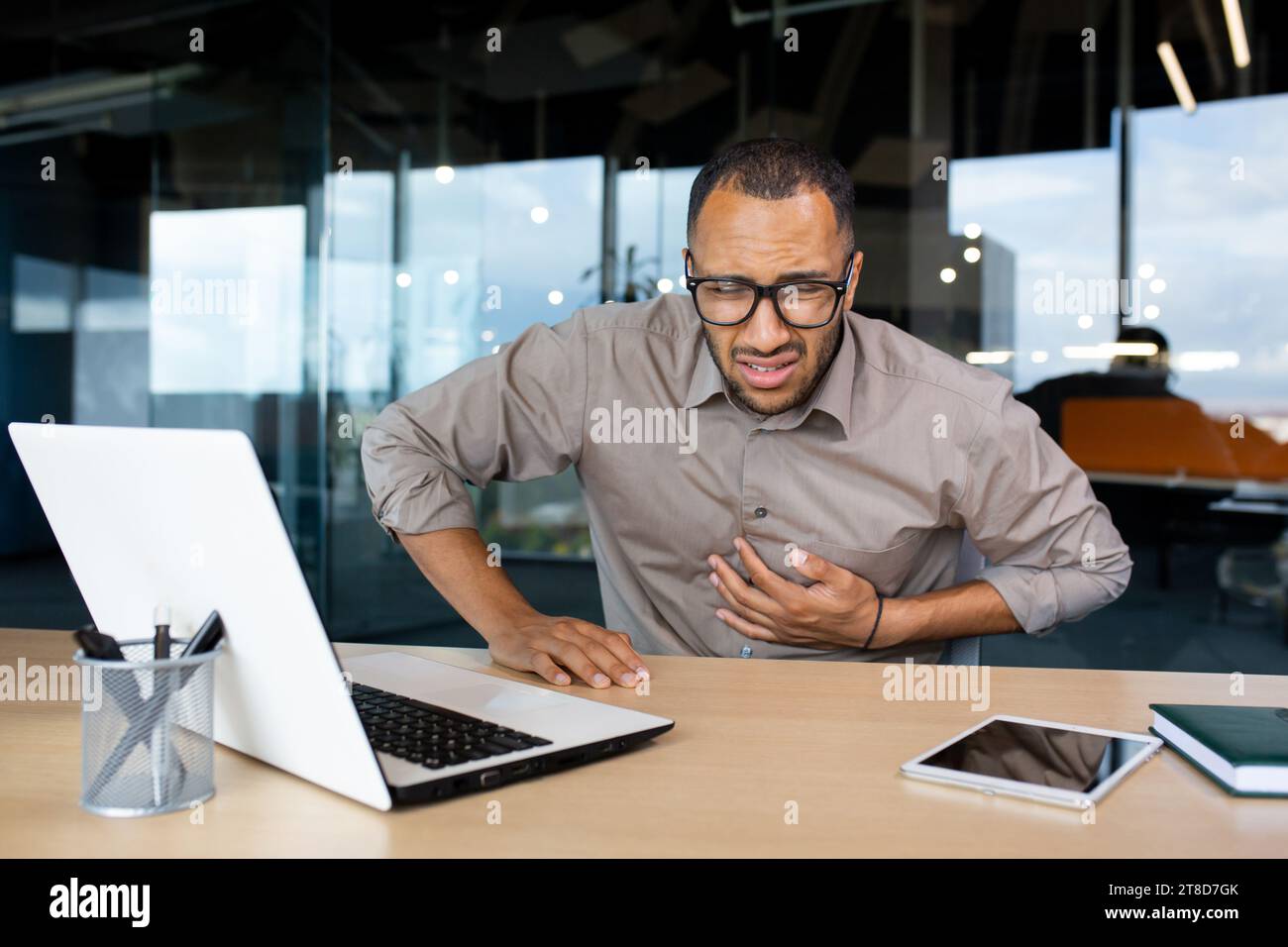 Man in the office holding his hand on his chest, heart attack at the ...