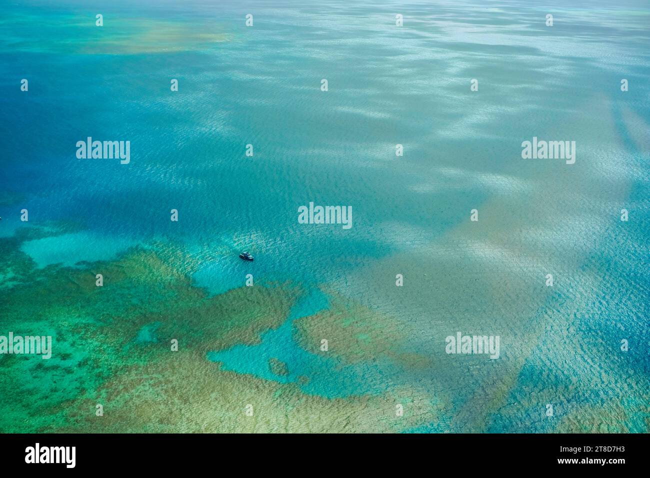 An aerial view of a boat making its way over the coral reefs and ...