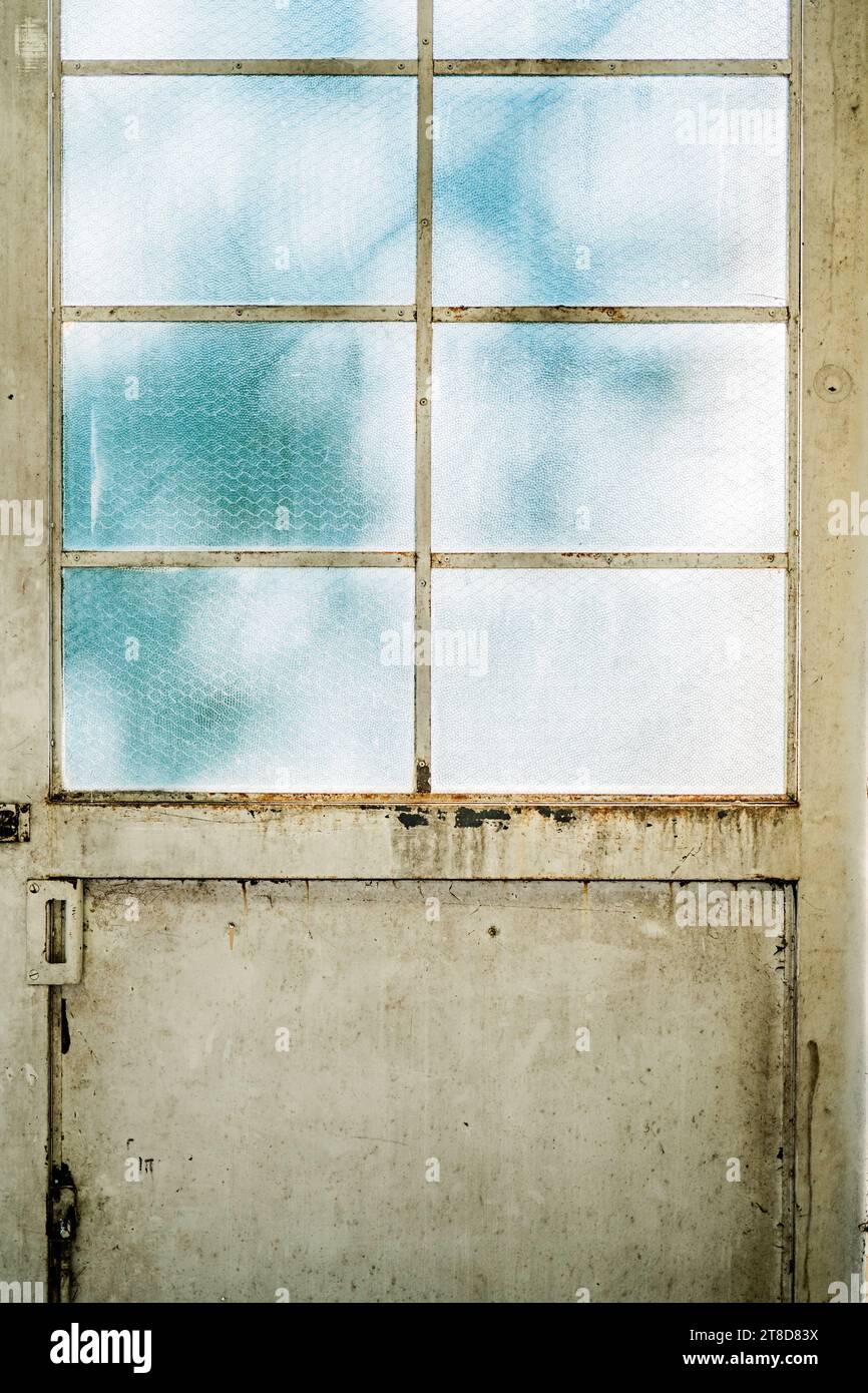 A white metallic door with a windowed panel and a shiny, silver handle ...