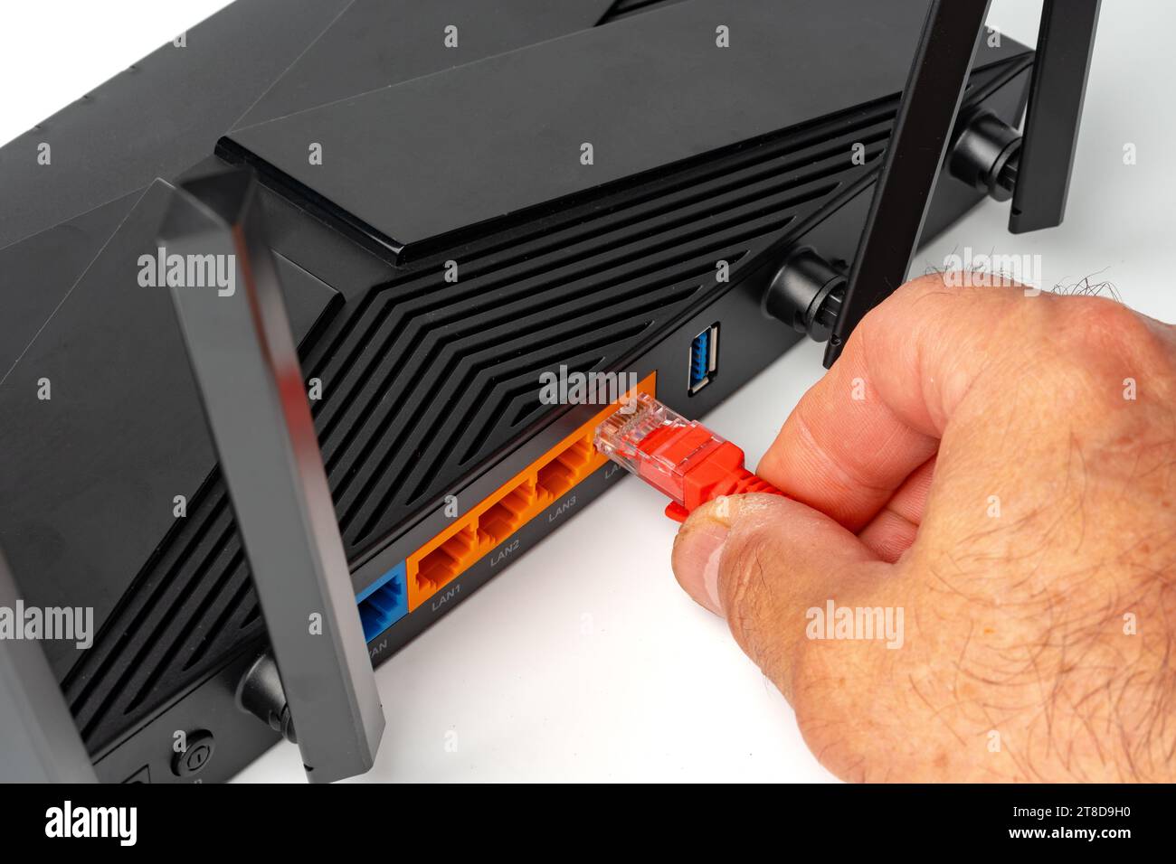 Man's hand plugging internet cable into wifi router Stock Photo - Alamy