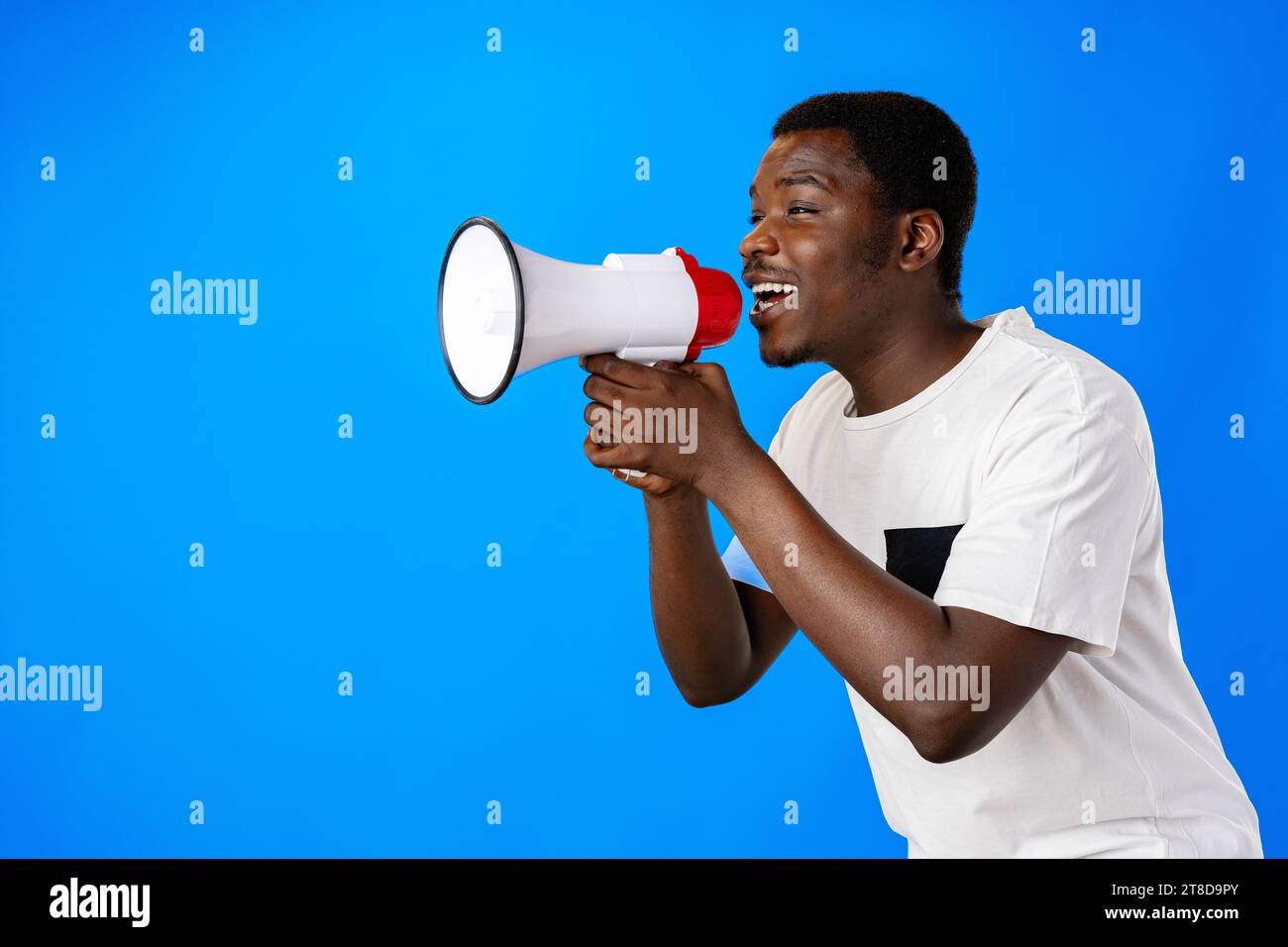 Positive african guy shouting with megaphone over blue background Stock ...