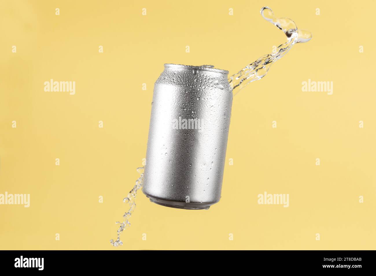 Aluminium beer or soda drinking can with water splash on light yellow ...