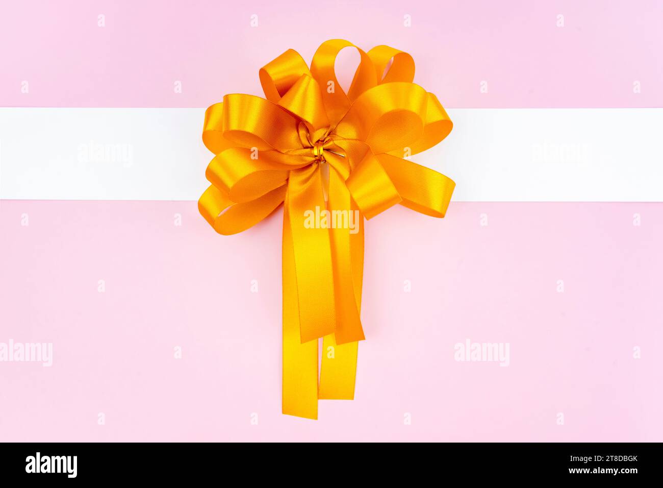 Golden color ribbon bow on pink color background Stock Photo - Alamy