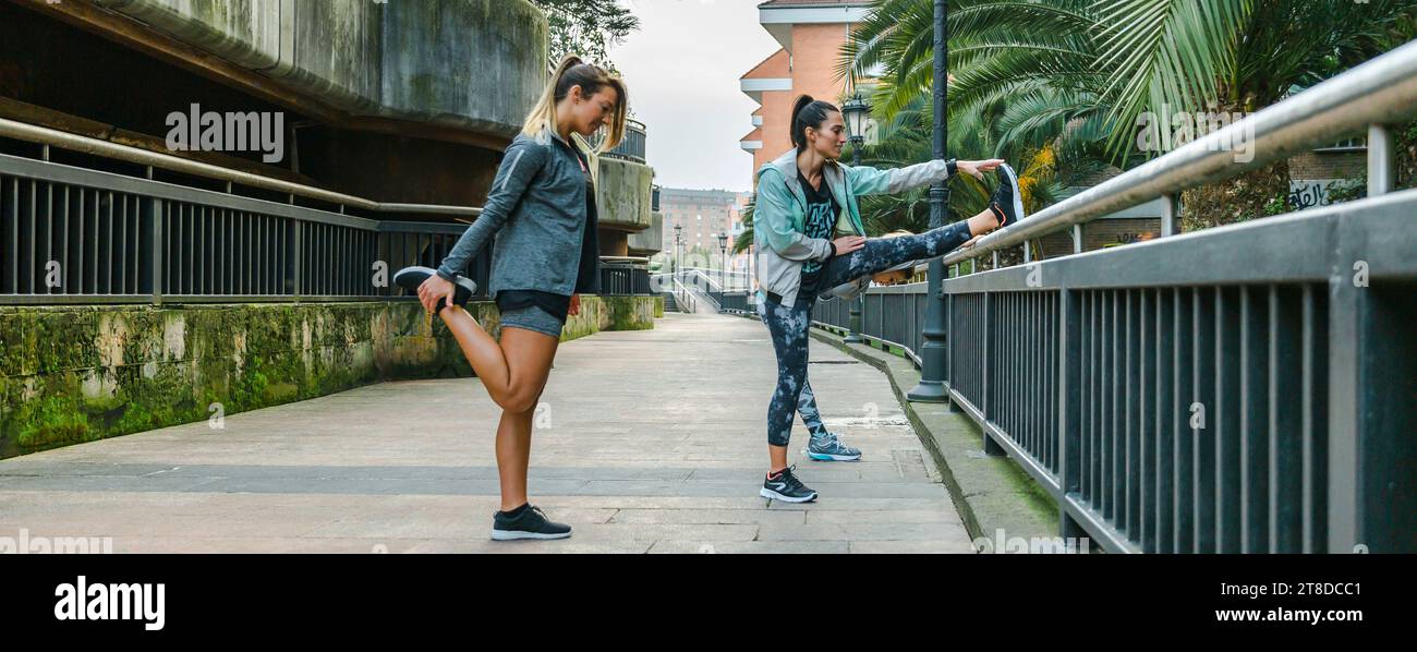 Women runners stretching legs before training on town Stock Photo - Alamy