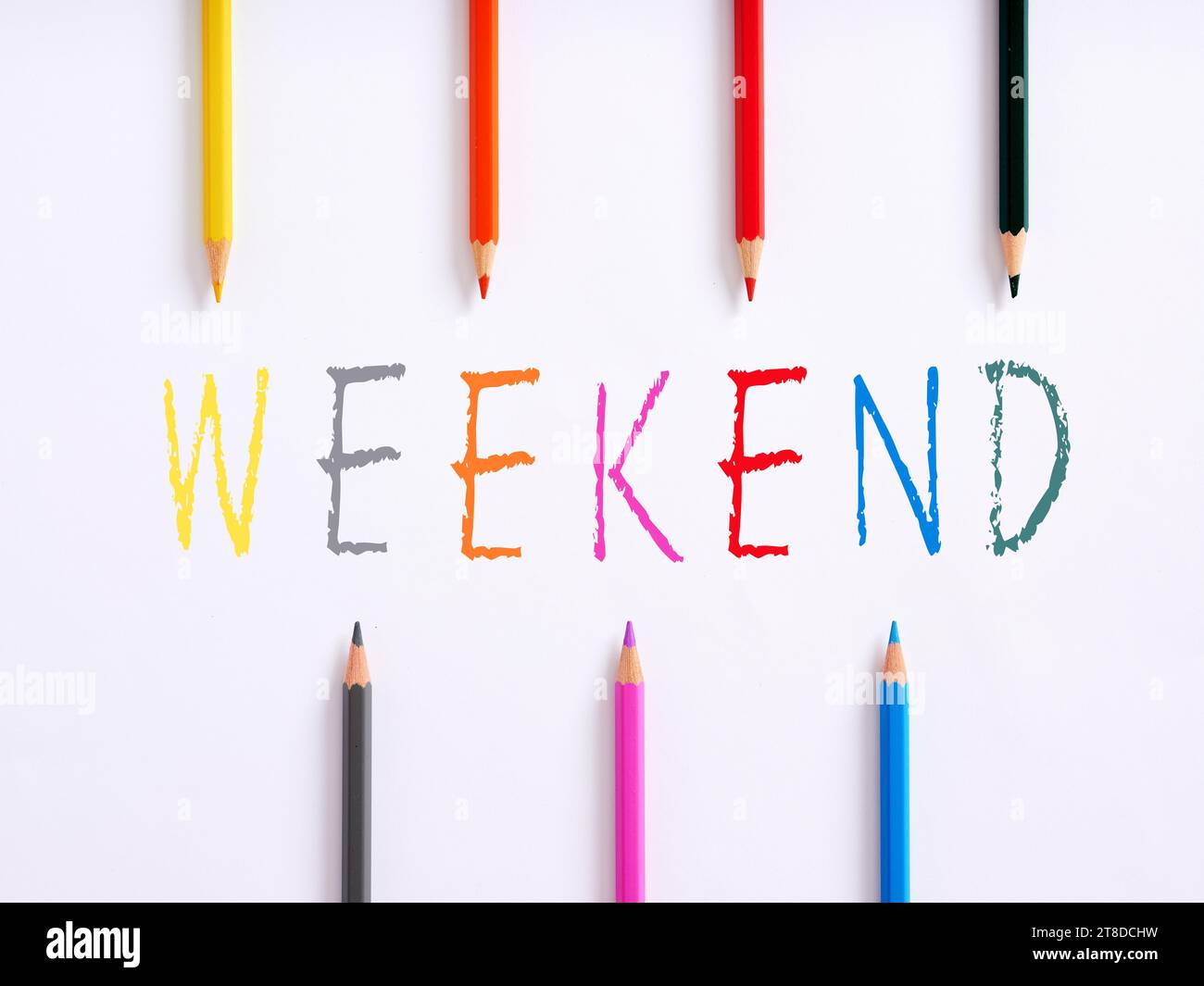 Handwritten word weekend and colorful crayons on white background ...