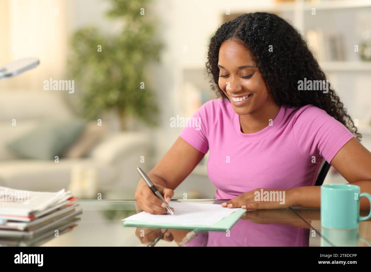 Happy black woman filling form sitting at home Stock Photo - Alamy