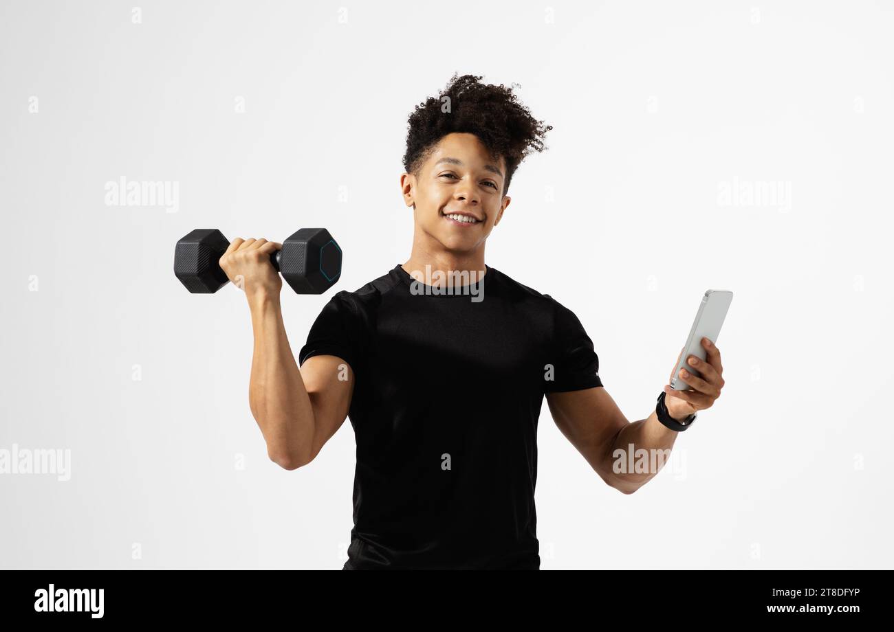 Athletic hispanic man grips dumbbell and smartphone over white ...