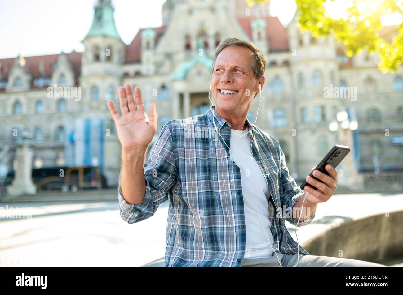 Man enjoying sightseeing in new city smiling happily using mobile phone ...
