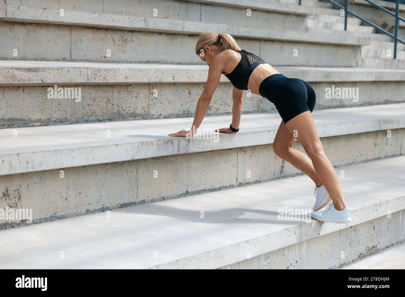 Sportswoman doing push ups exercises or plank on stairs in morning ...