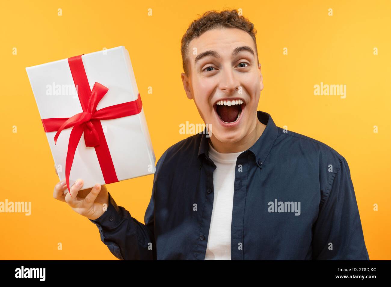 Happy young guy holding wrapped box, feeling excited on yellow Stock ...