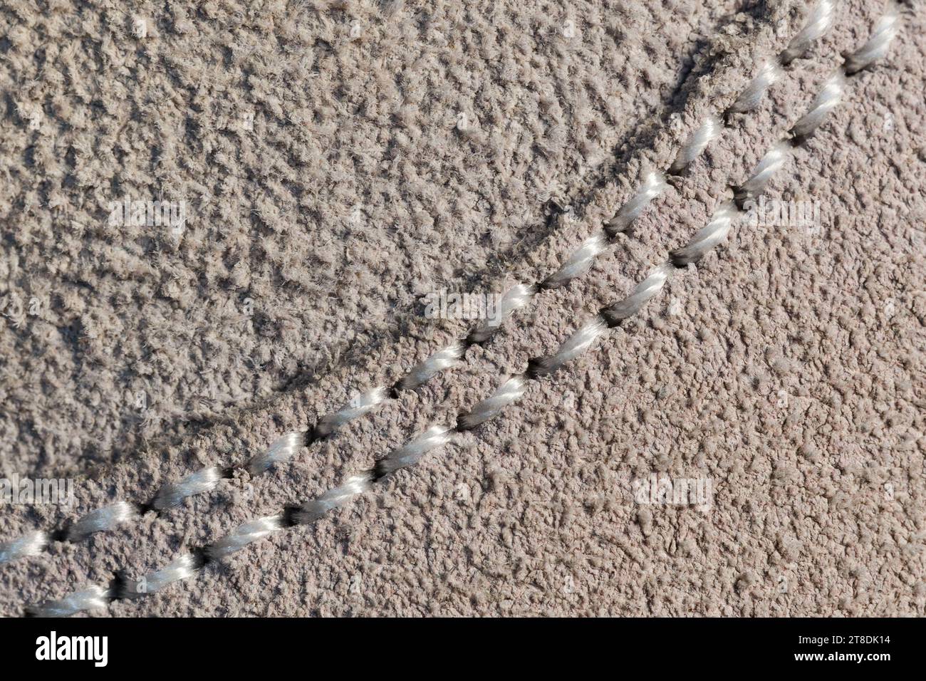 Two pieces of beige suede, sewn with double stitching with white ...