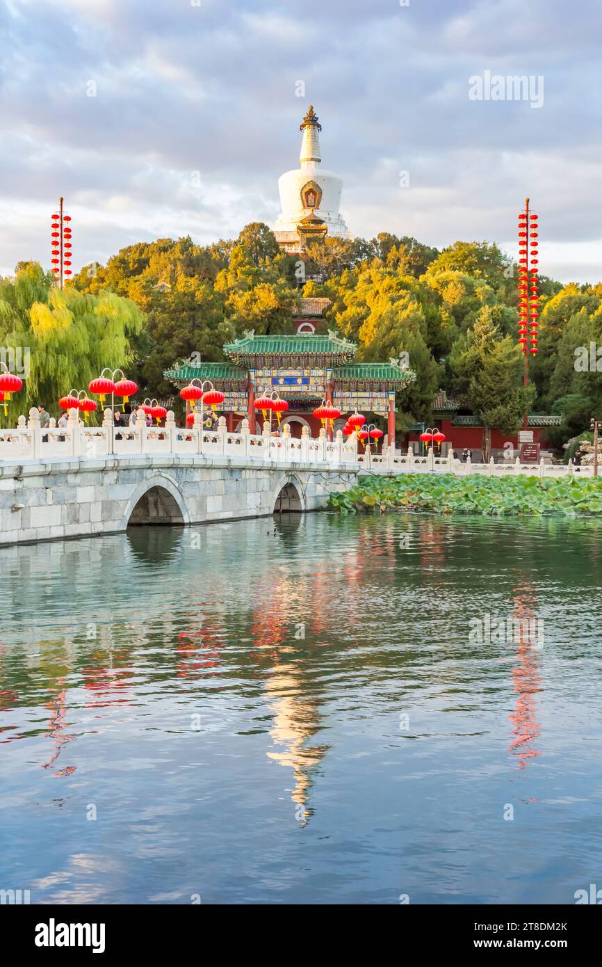 Historic white Bai Ta tower reflected in the water in Beihai Park in ...