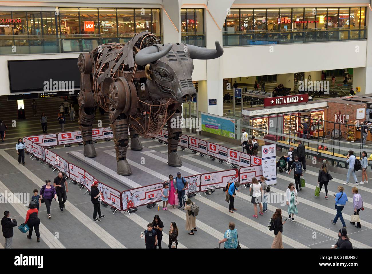 People waiting for trains next to Ozzy the bull at New Street Railway ...