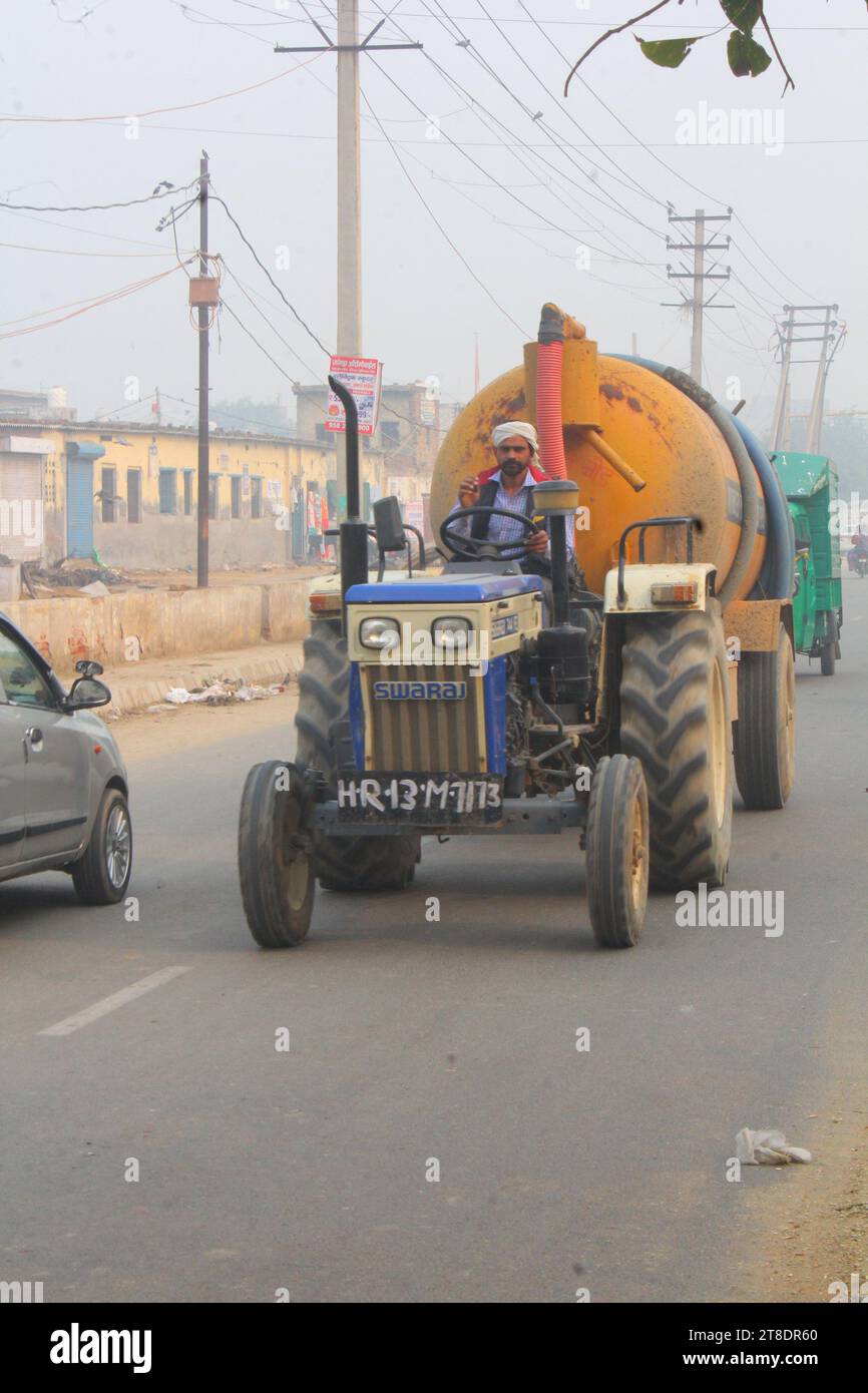 A blue tractor which is pulling a yellow tanker trailer is running in ...