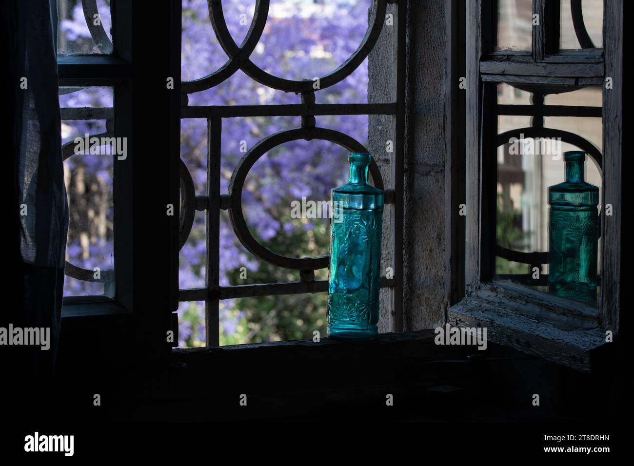 Antique, turquoise blue glass bottle sits in the window of an old ...