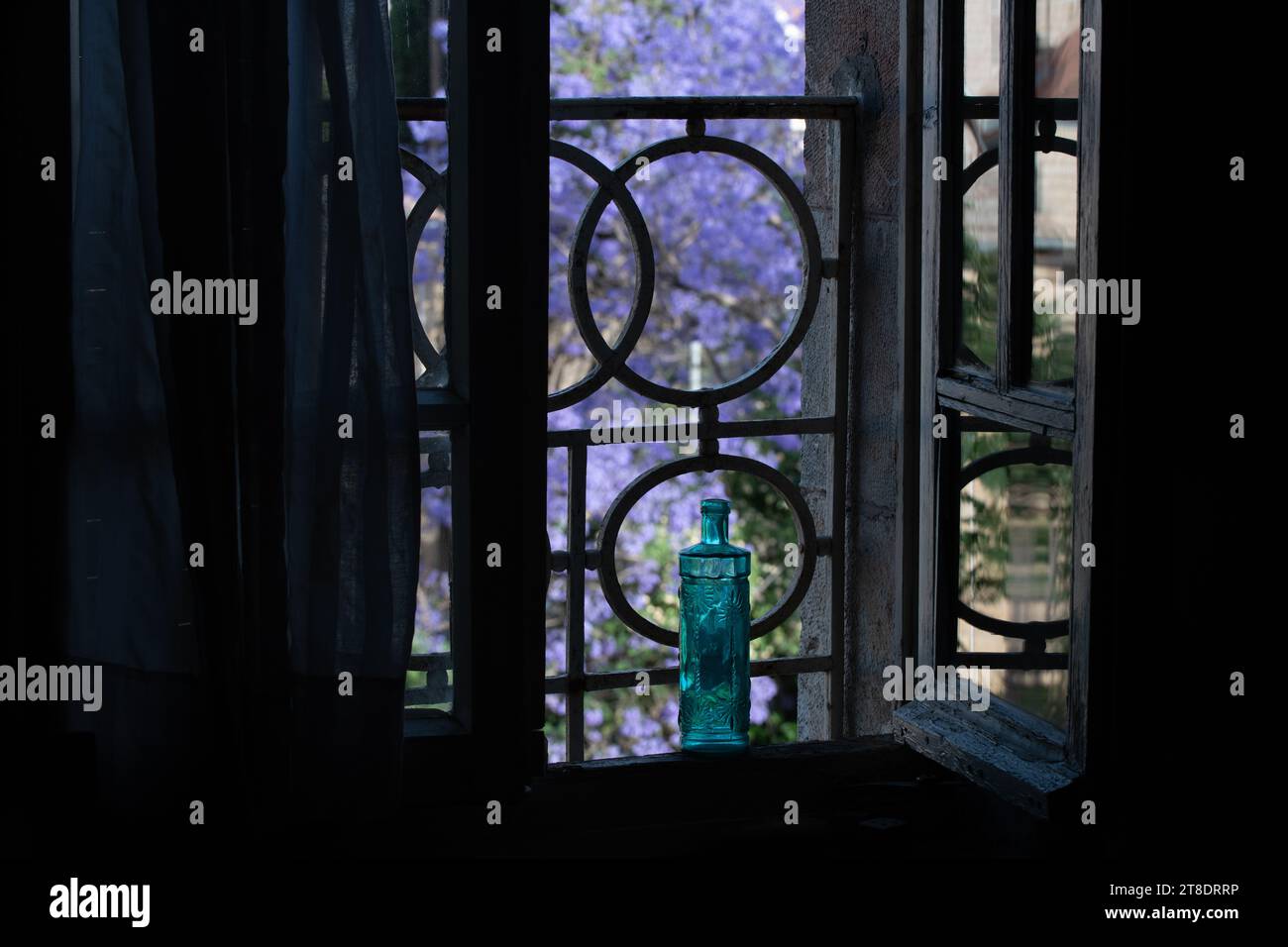 Antique, turquoise blue glass bottle sits in the window of an old ...