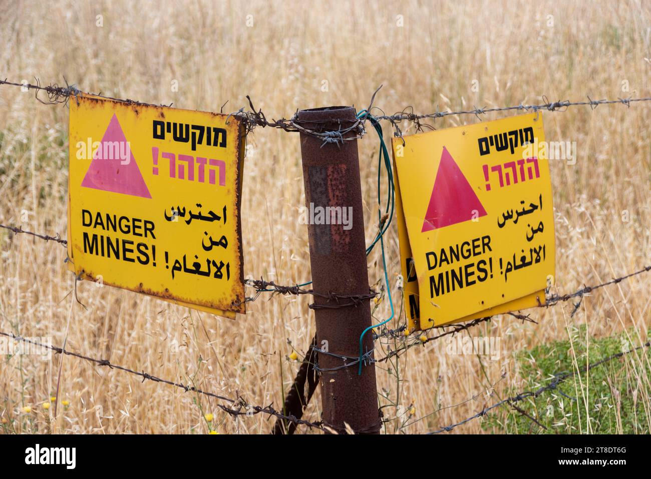 A sign hanging on a barbed wire fence with English, Arabic and Hebrew ...