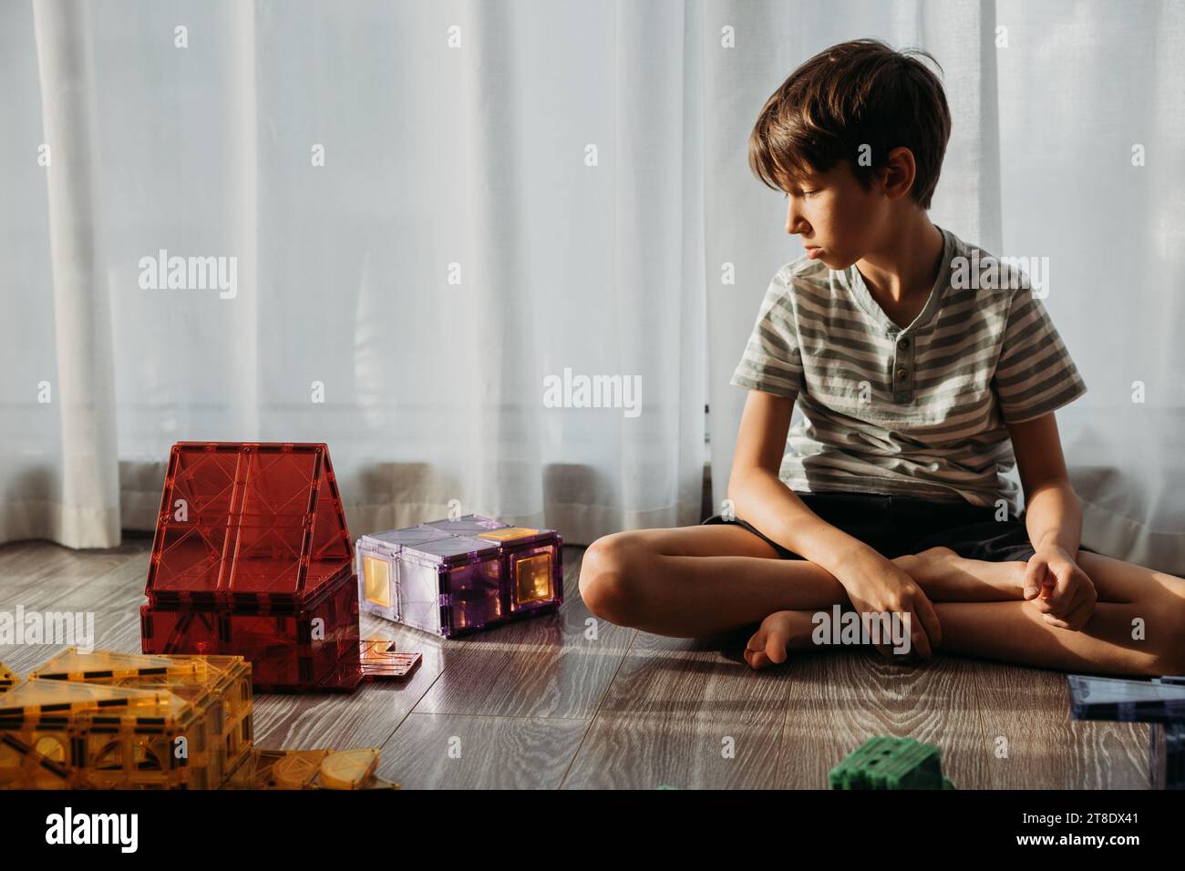 Sad boy sitting on the floor with a designer in the kids room Stock ...