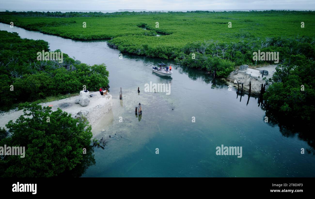 A group of people standing on a boat floating down a river surrounded ...